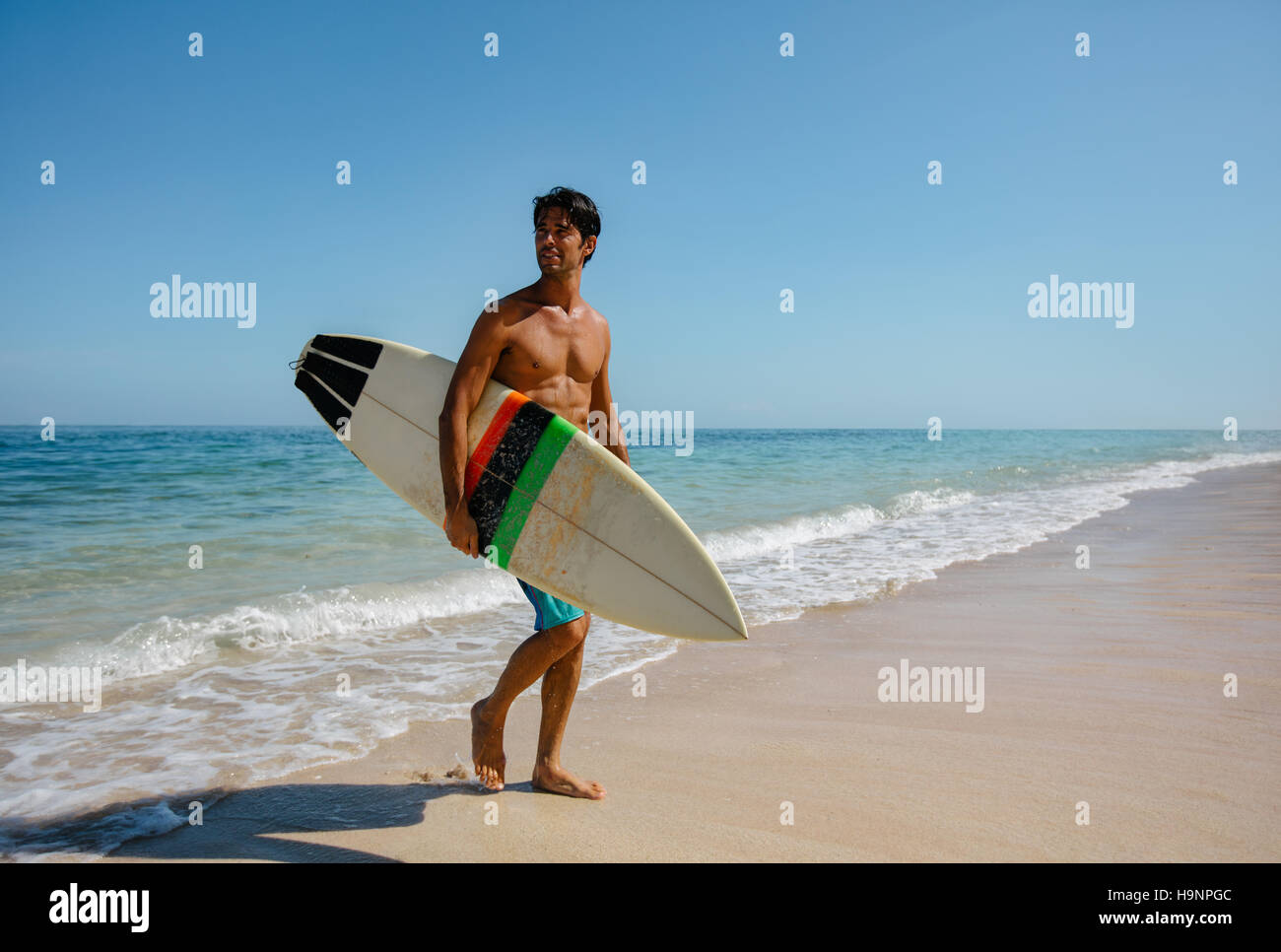 Full length shot of young man with surf board on beach. Handsome ...