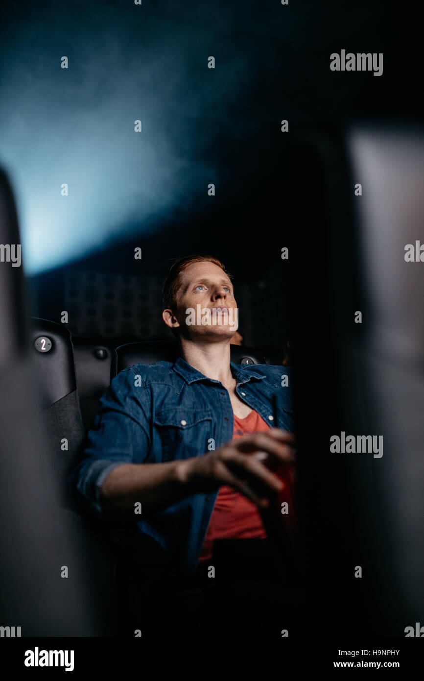 Young man watching movie in theater. Caucasian male watching film in ...