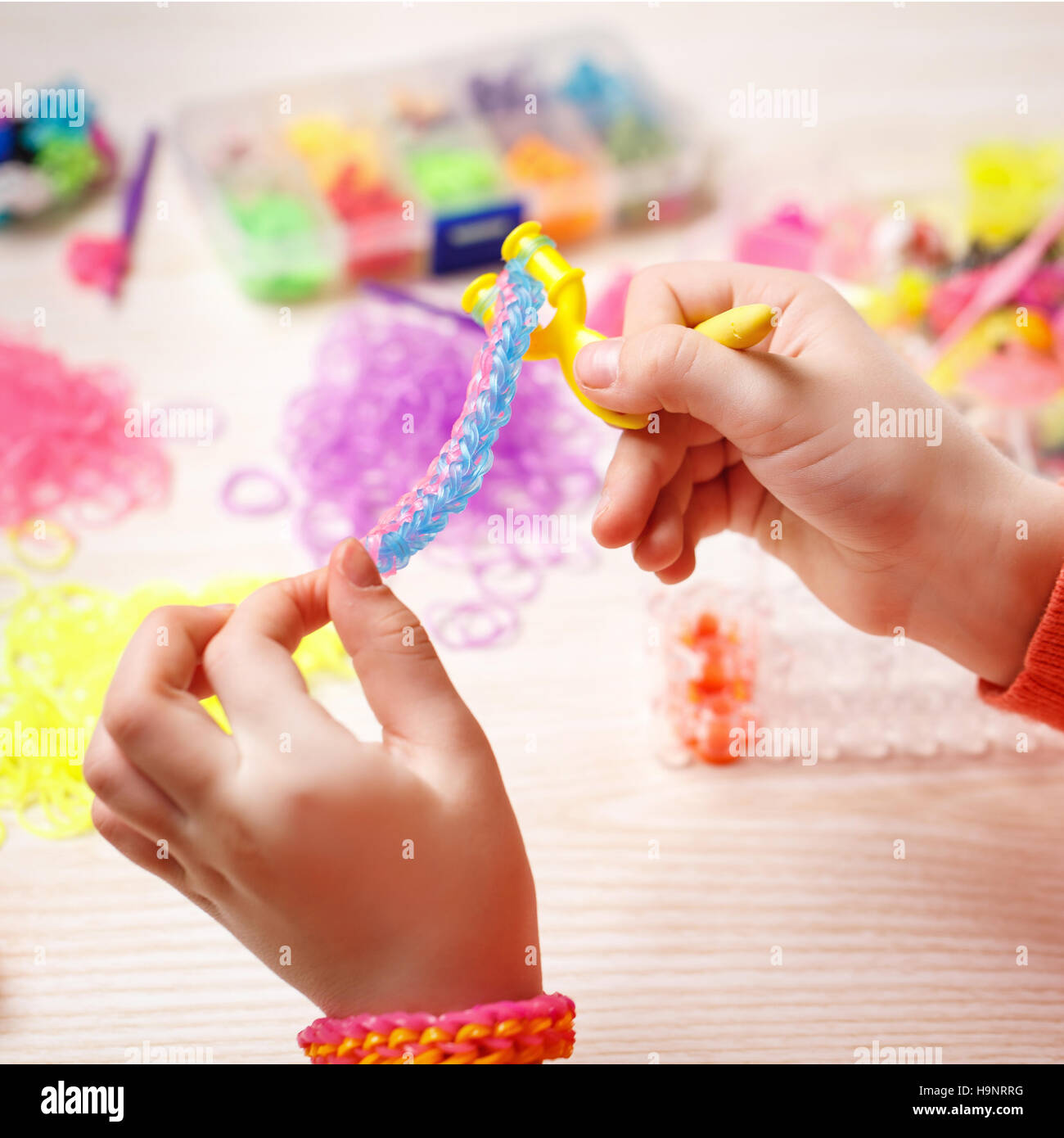 hands weaving of rubber band bracelet, closeup, wooden background Stock ...