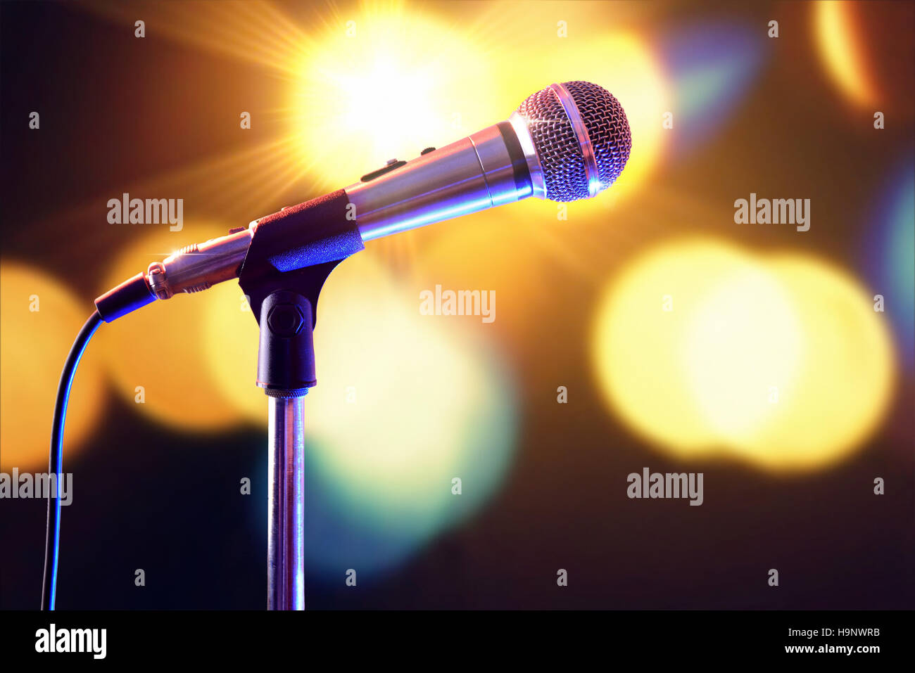 Microphone on microphone stand with cable and lights in the background ...