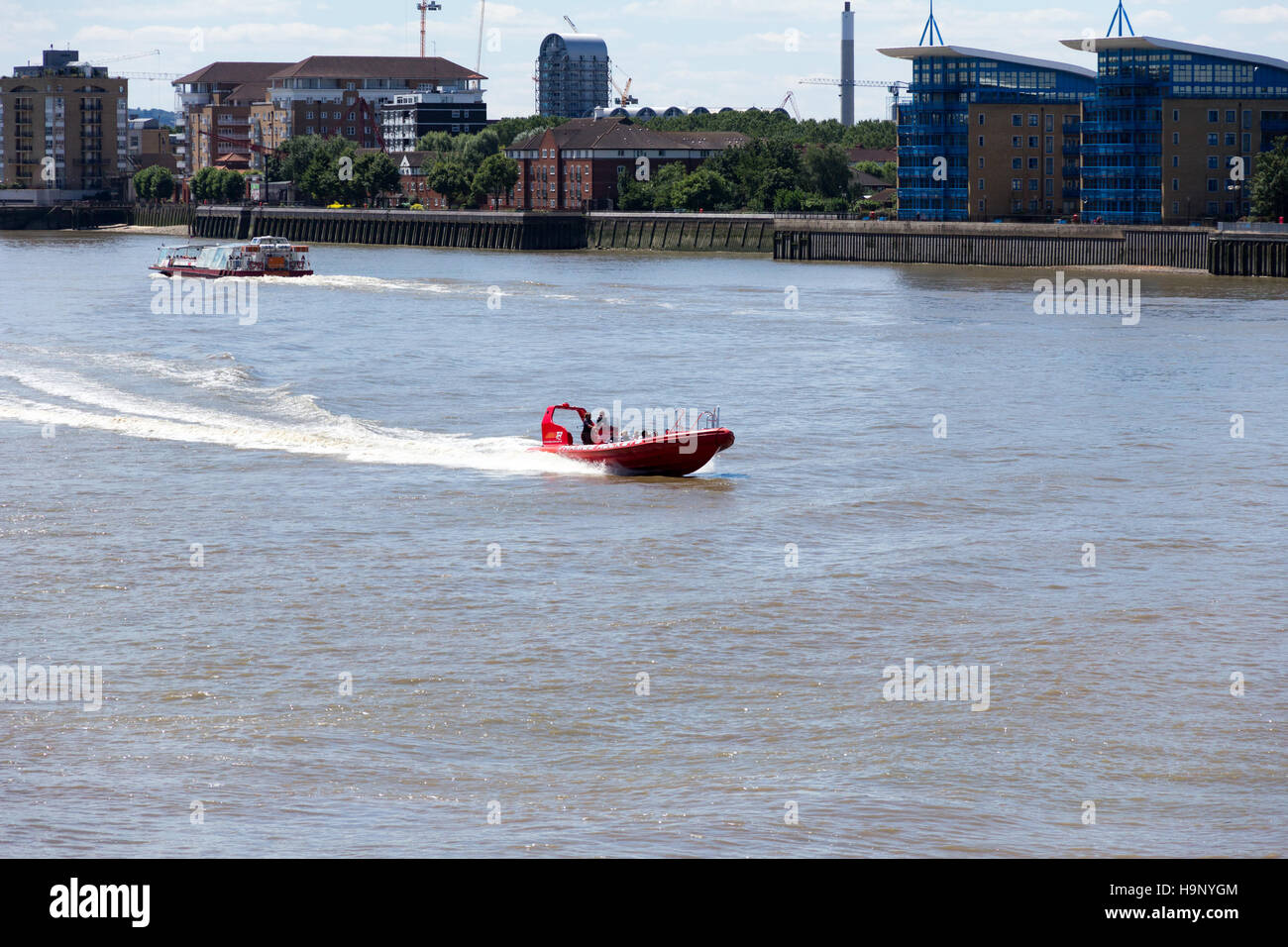 A ferry and speedboat travelling along the River Thames near Canary ...