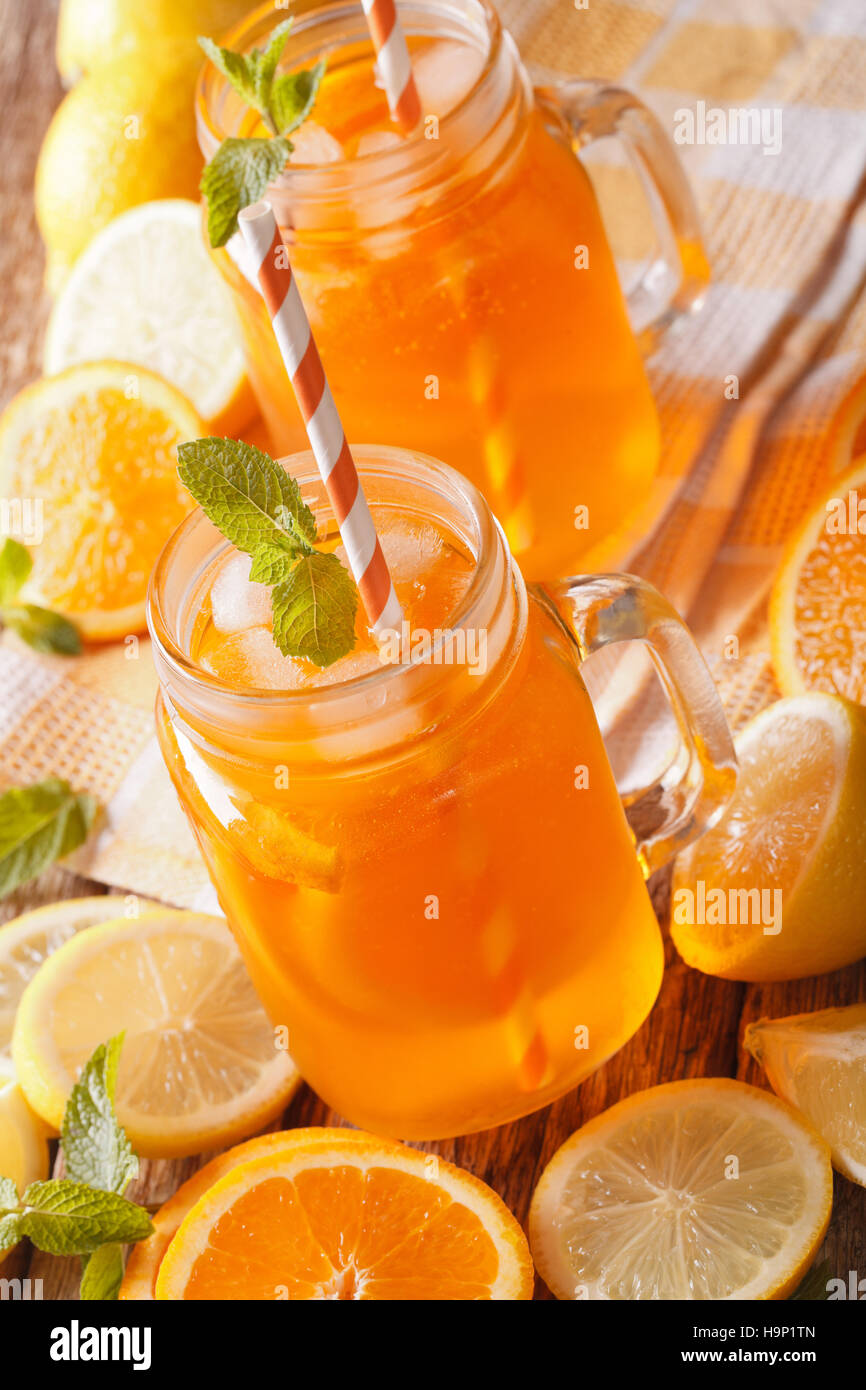 cold orange drink with lemon, mint and ice close-up on the table ...