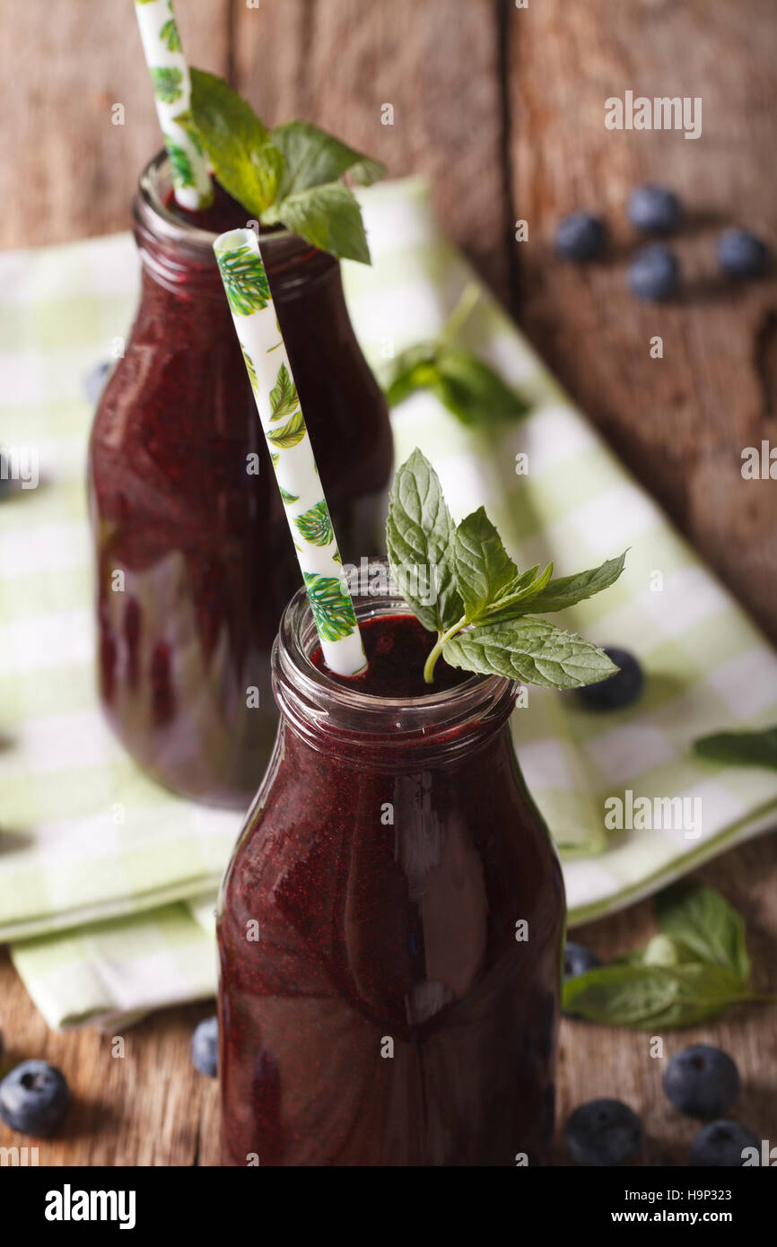 Fresh healthy blueberry juice in a glass bottle on a table macro ...