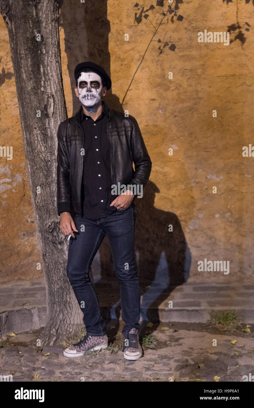 A young man dressed as the dapper skeleton rests along a street during ...