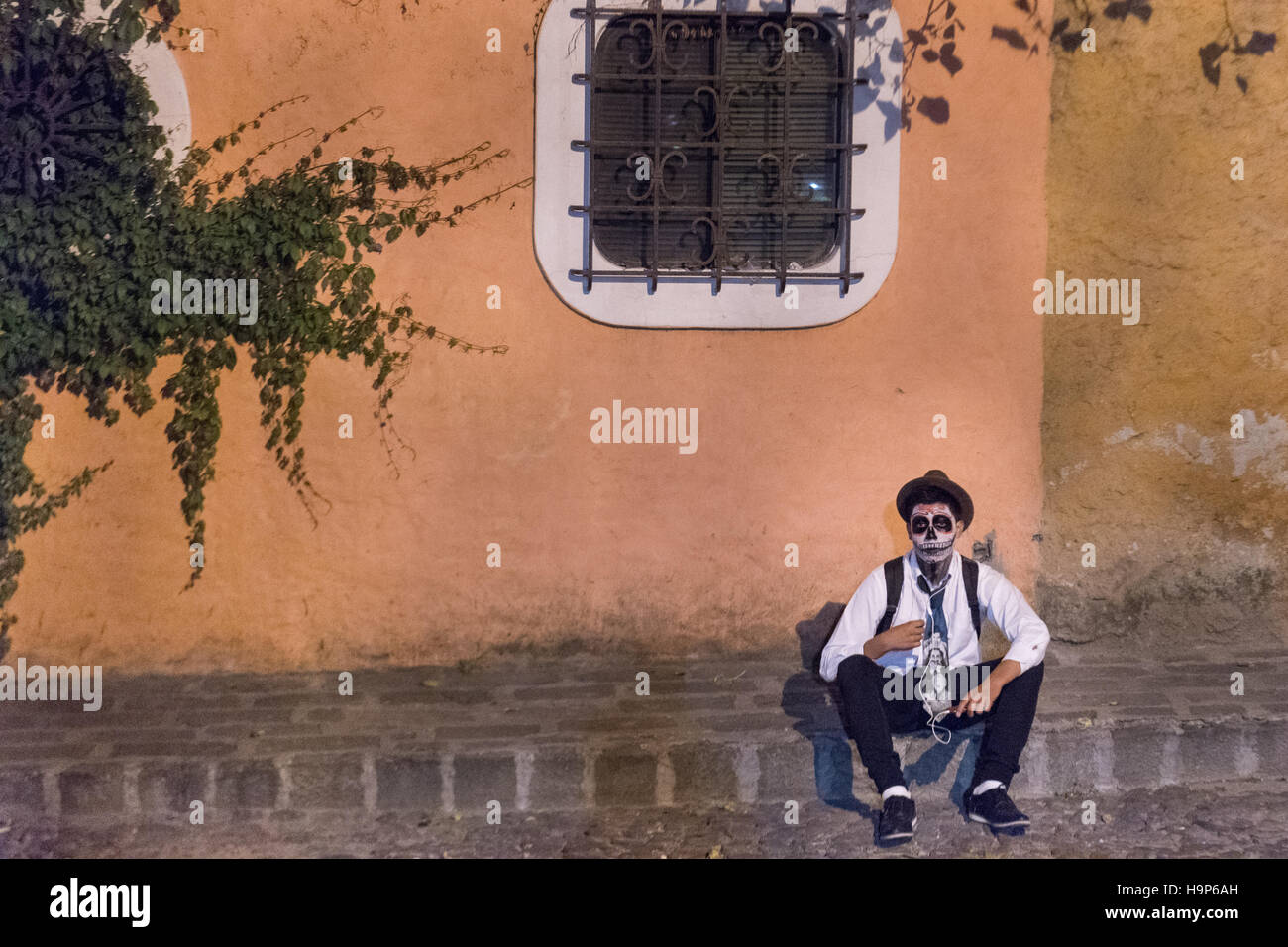 A young man dressed as the dapper skeleton rests along a street during ...