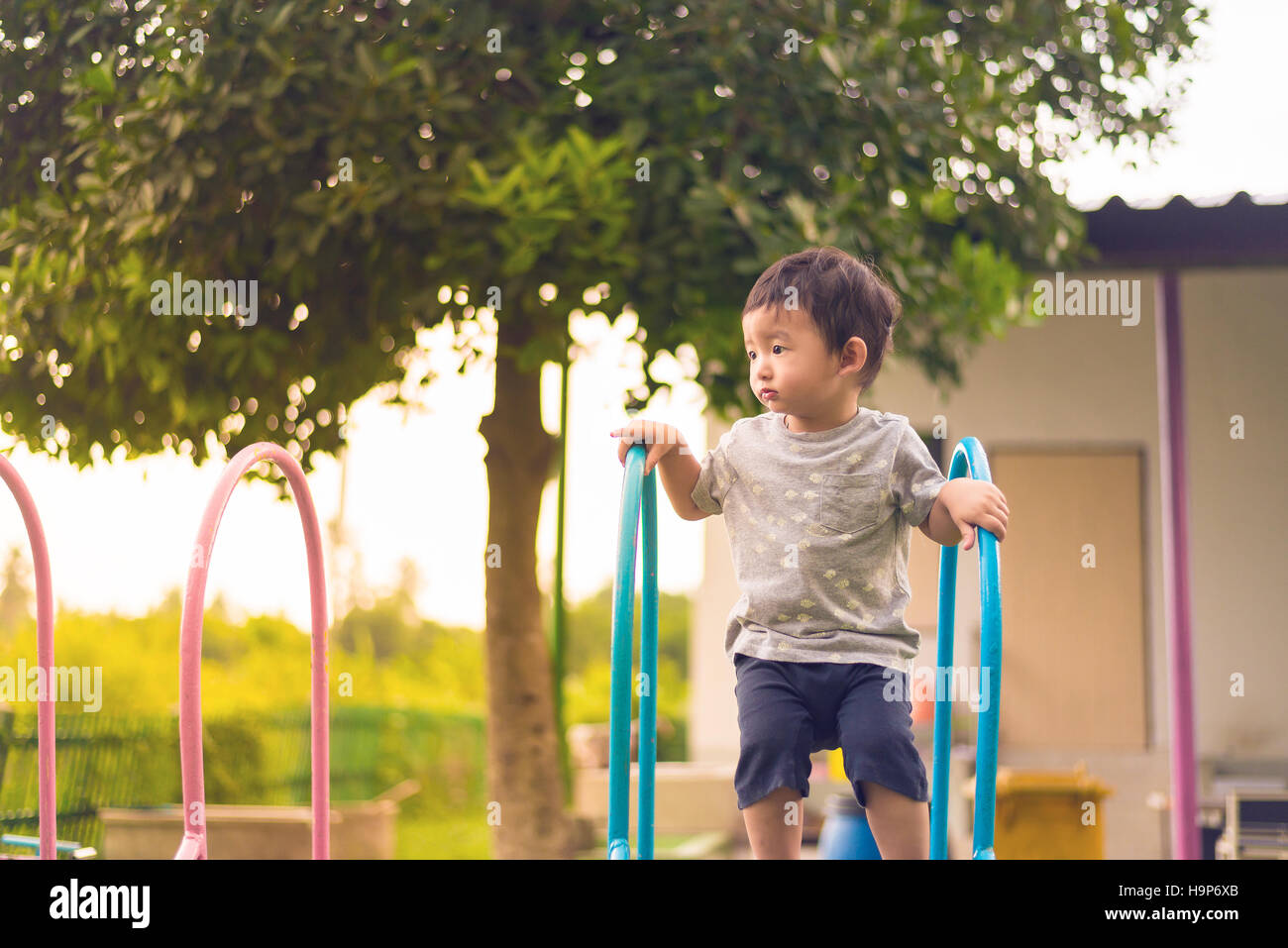 Little Asian kid playing slide at the playground under the sunlight in ...