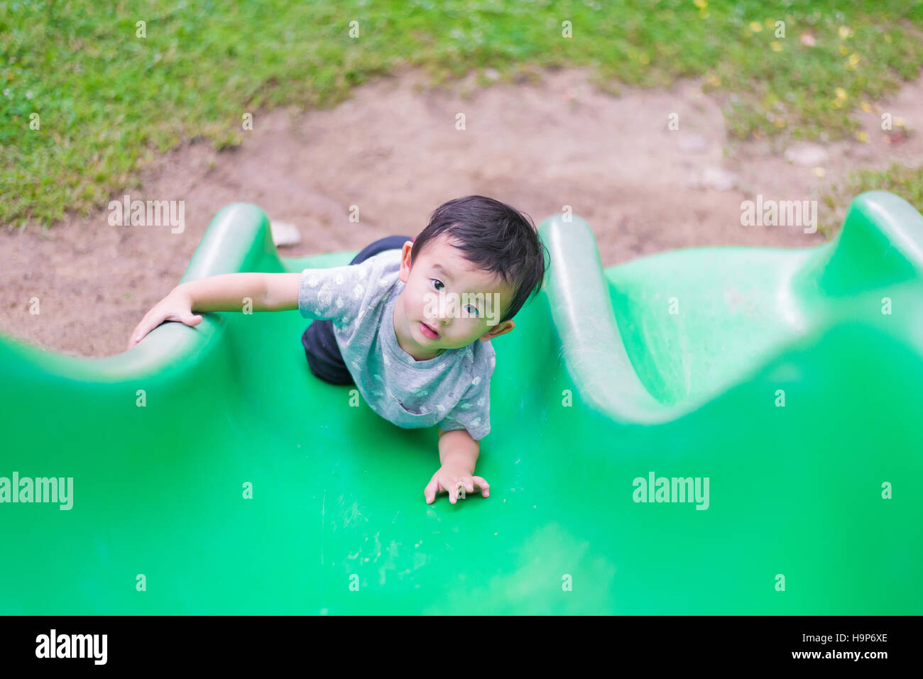 Little Asian kid climbing up the slide at the playground under the ...