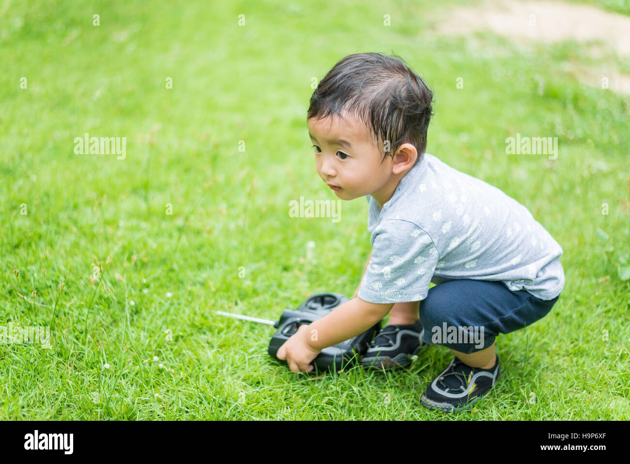 Little Asian kid holding a radio remote control (controlling handset ...
