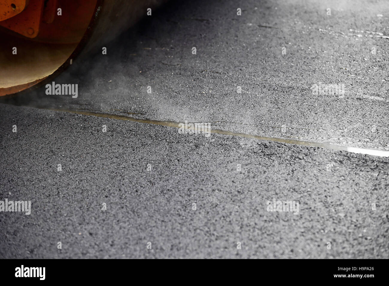 Asphalt paving with a steel wheel roller. Steam coming out from asphalt ...