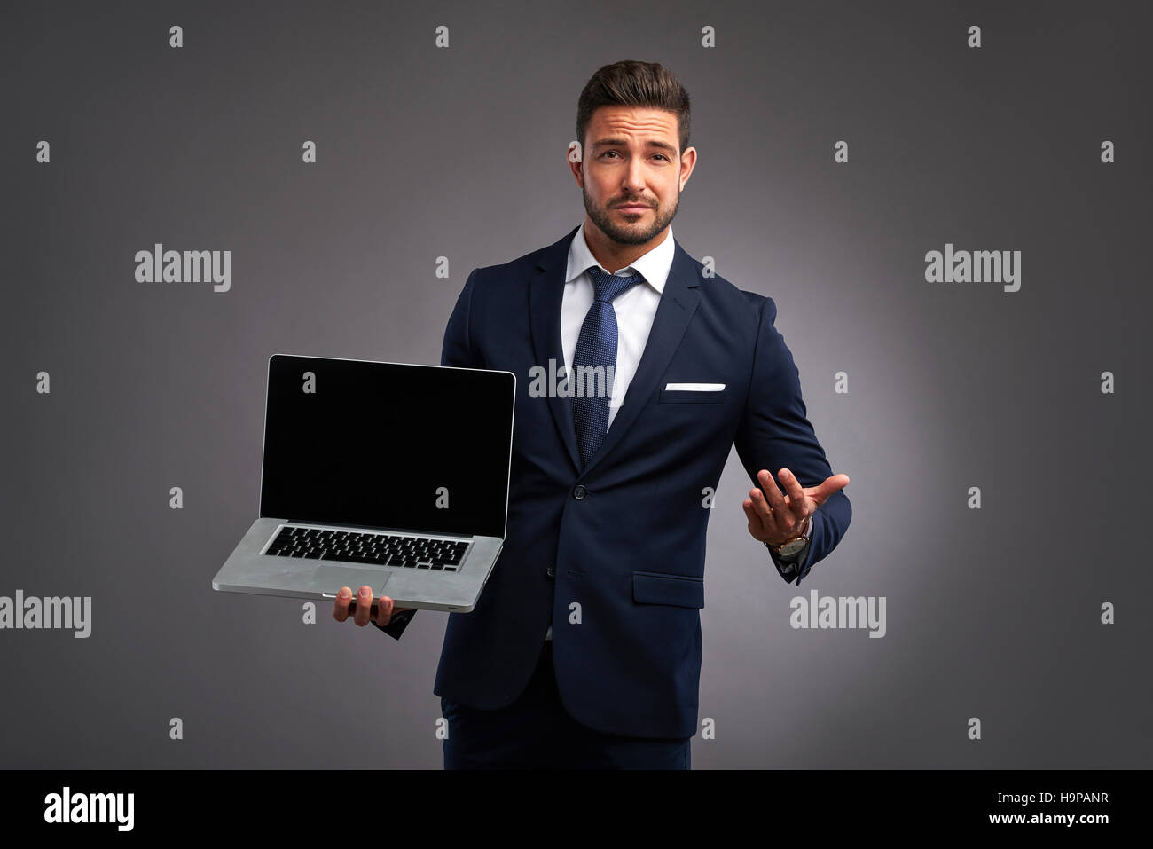 An elegant handsome young man holding and showing the screen of a ...