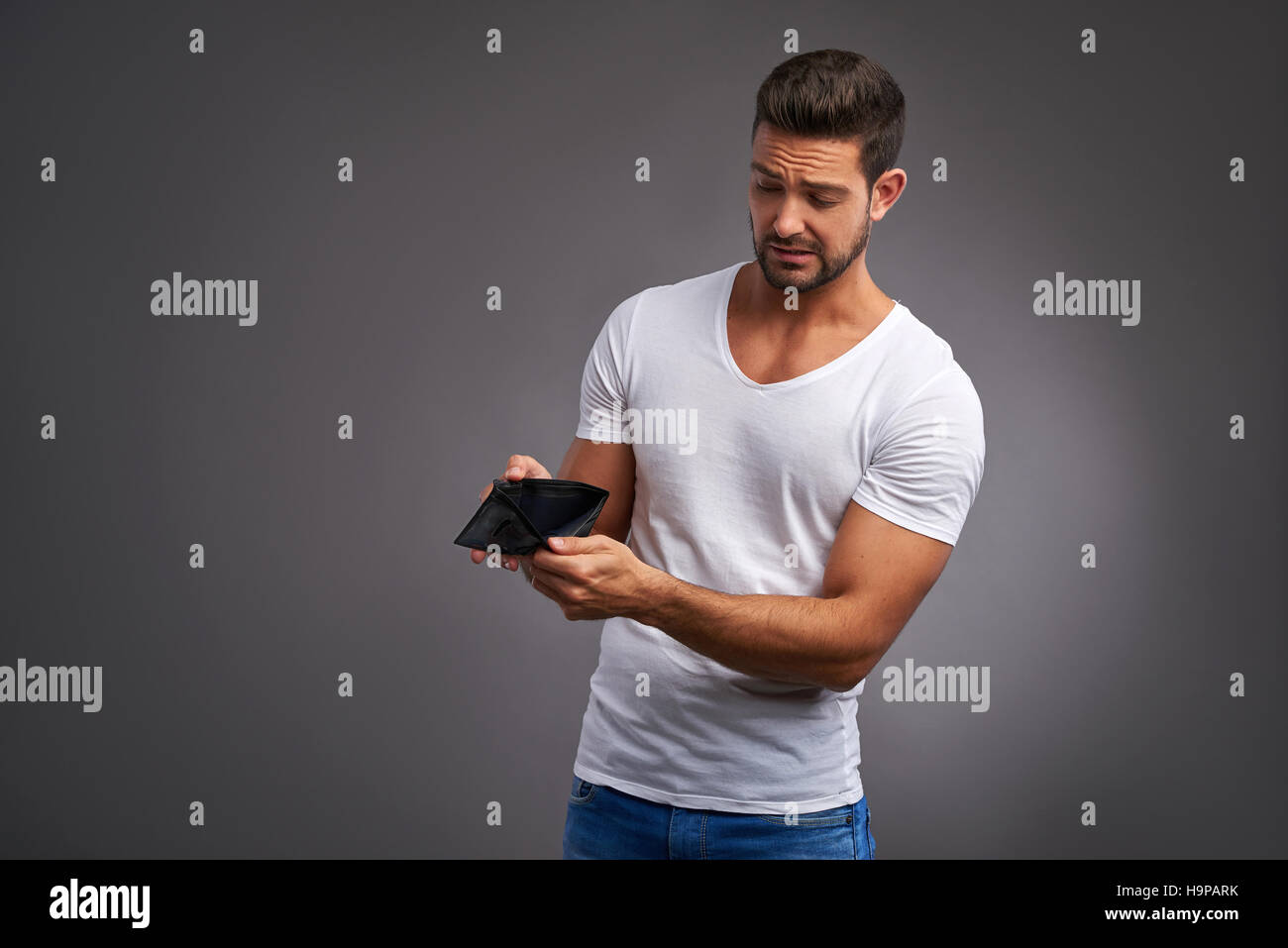 A poor handsome young man feeling stressed while looking at his empty ...