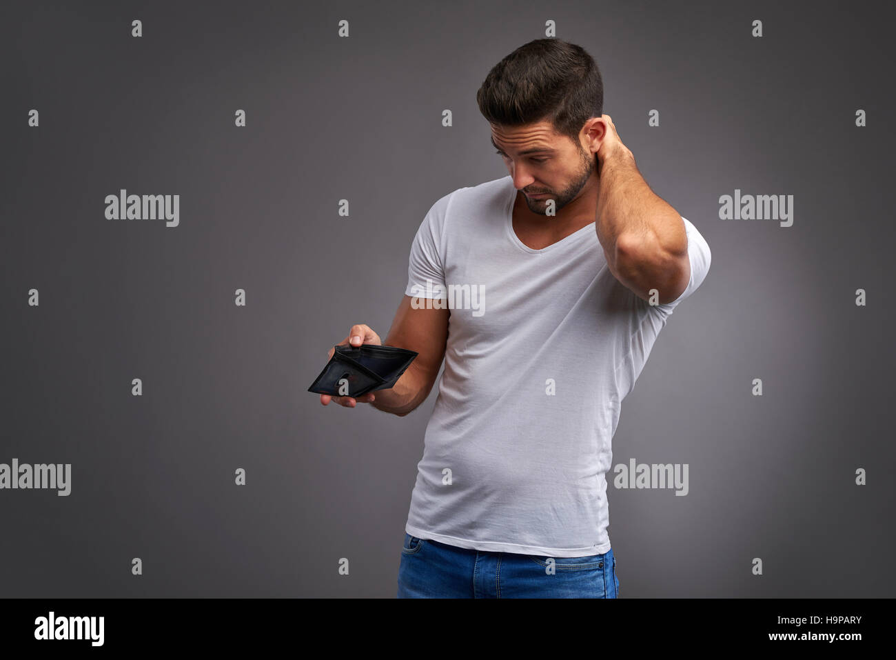 A poor handsome young man feeling stressed while looking at his empty ...