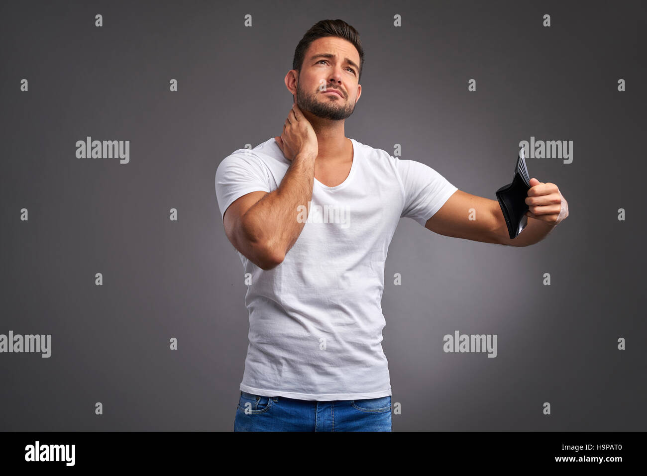 A poor handsome young man feeling stressed while looking at his empty ...