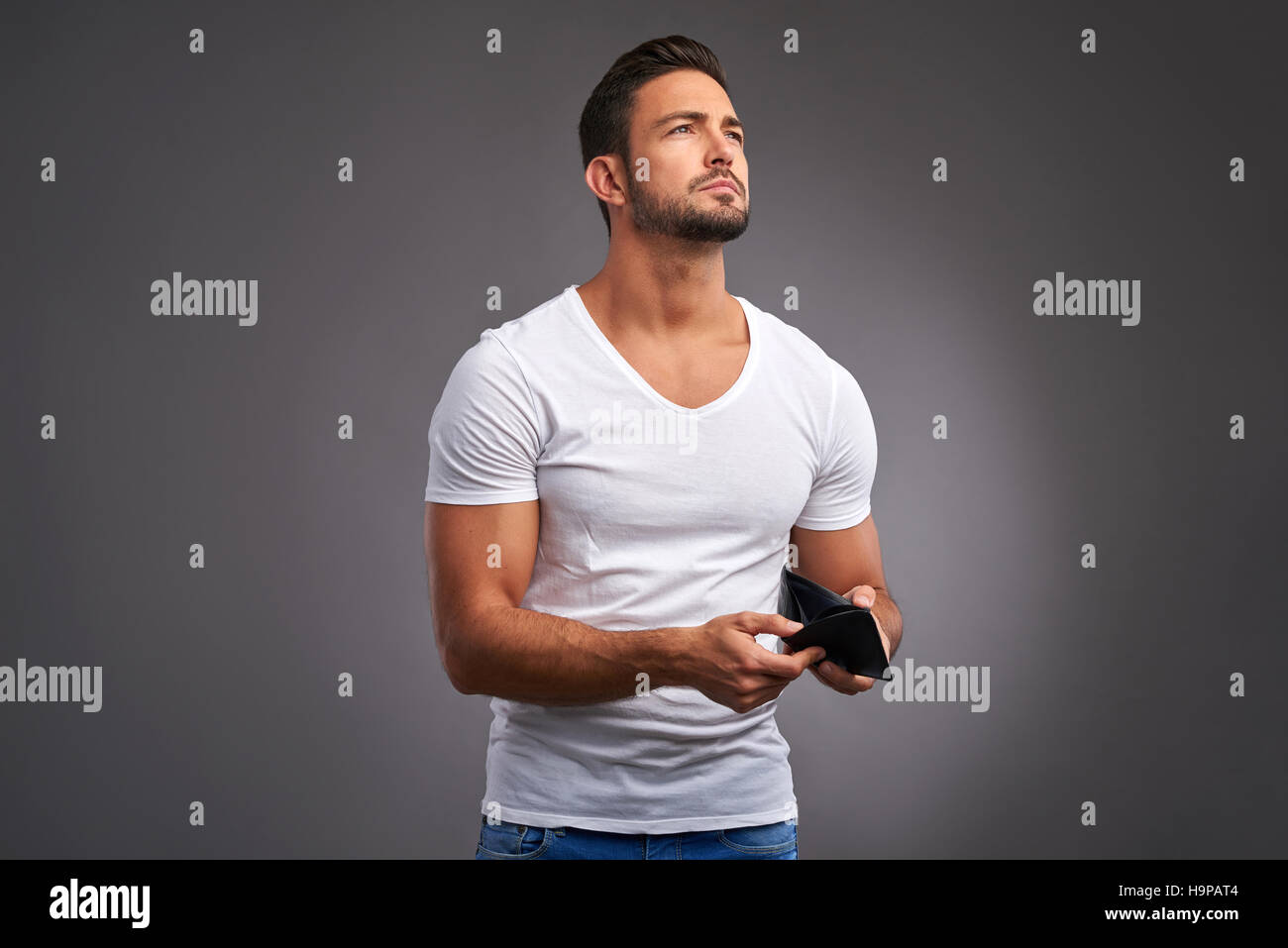 A poor handsome young man feeling stressed while looking at his empty ...