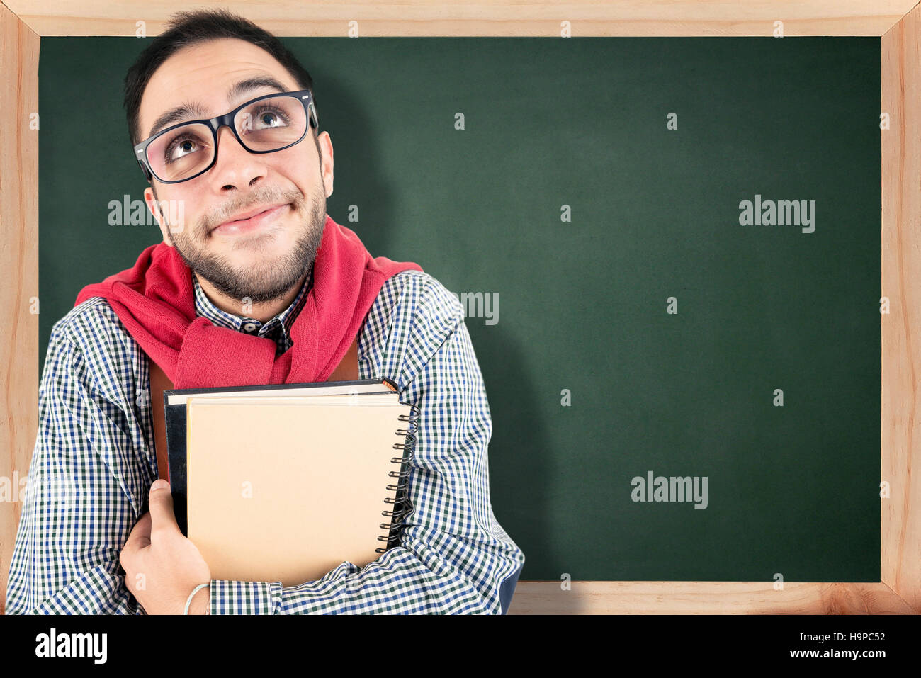 Nerd student posing with books against a chalk board Stock Photo - Alamy