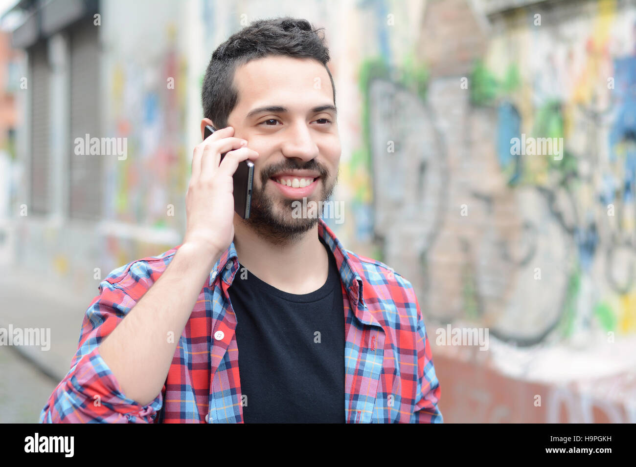Handsome young latin man talking on the phone. Trendy and urban scene ...