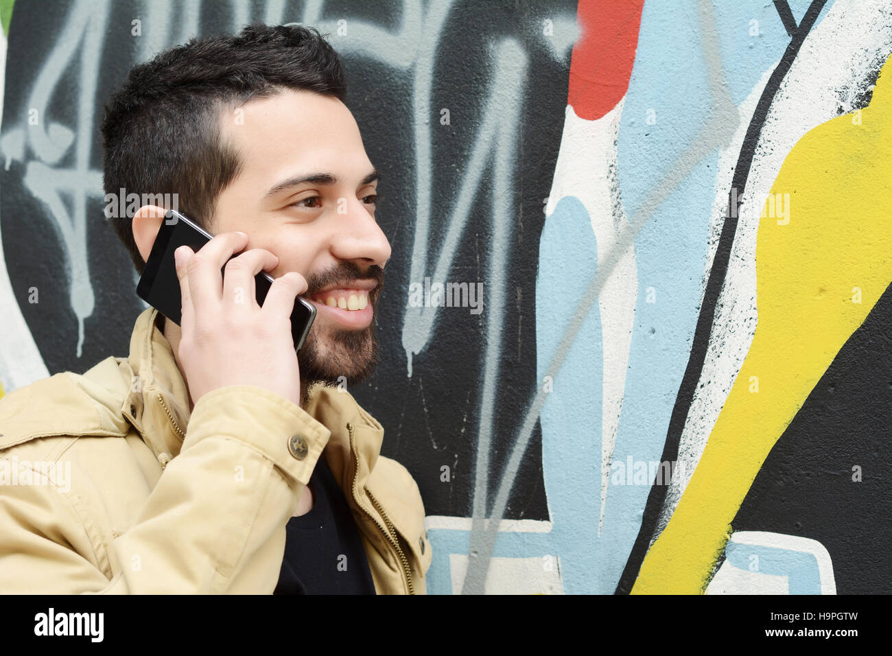Handsome young latin man talking on the phone. Trendy and urban scene ...