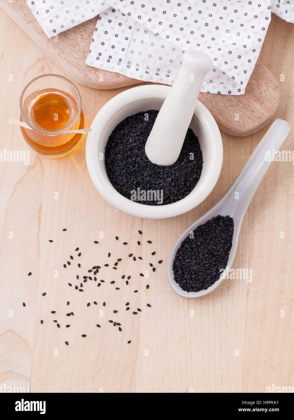 Black sesame oil and sesame seeds set up on wooden table Stock Photo ...