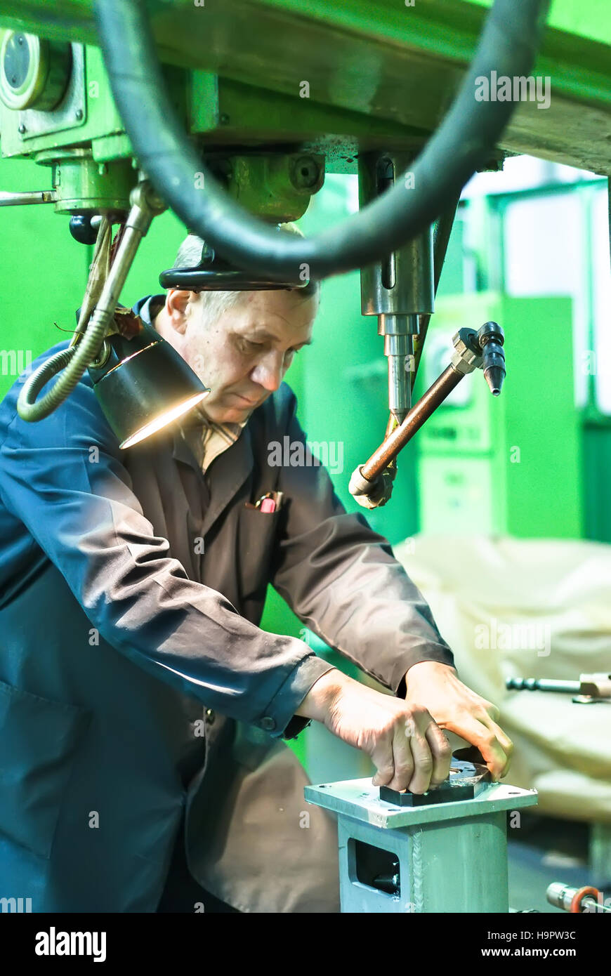 Elderly worker watches on milling machine work Stock Photo - Alamy