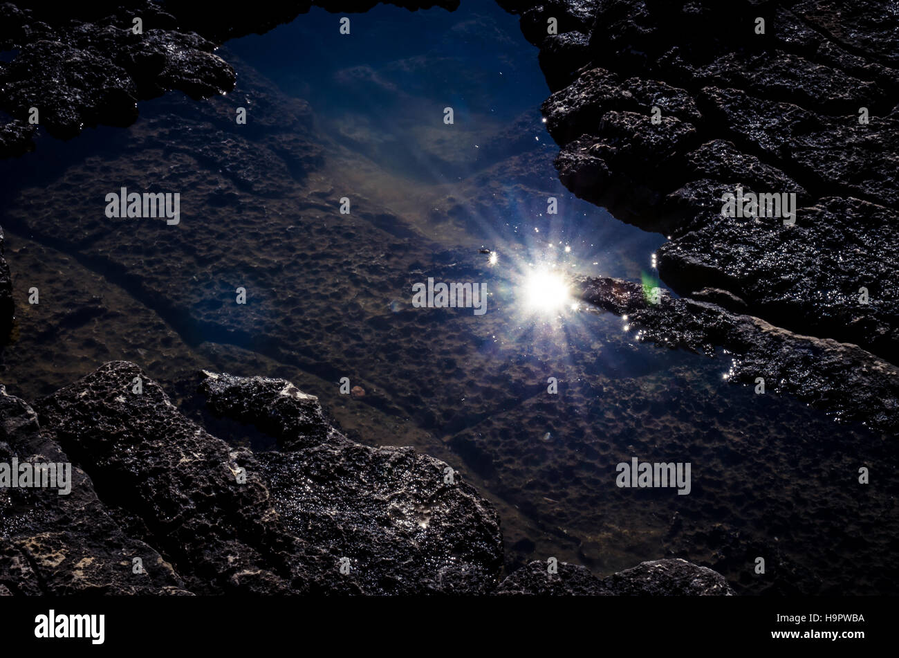 reflection of sun in water in rocks Stock Photo - Alamy