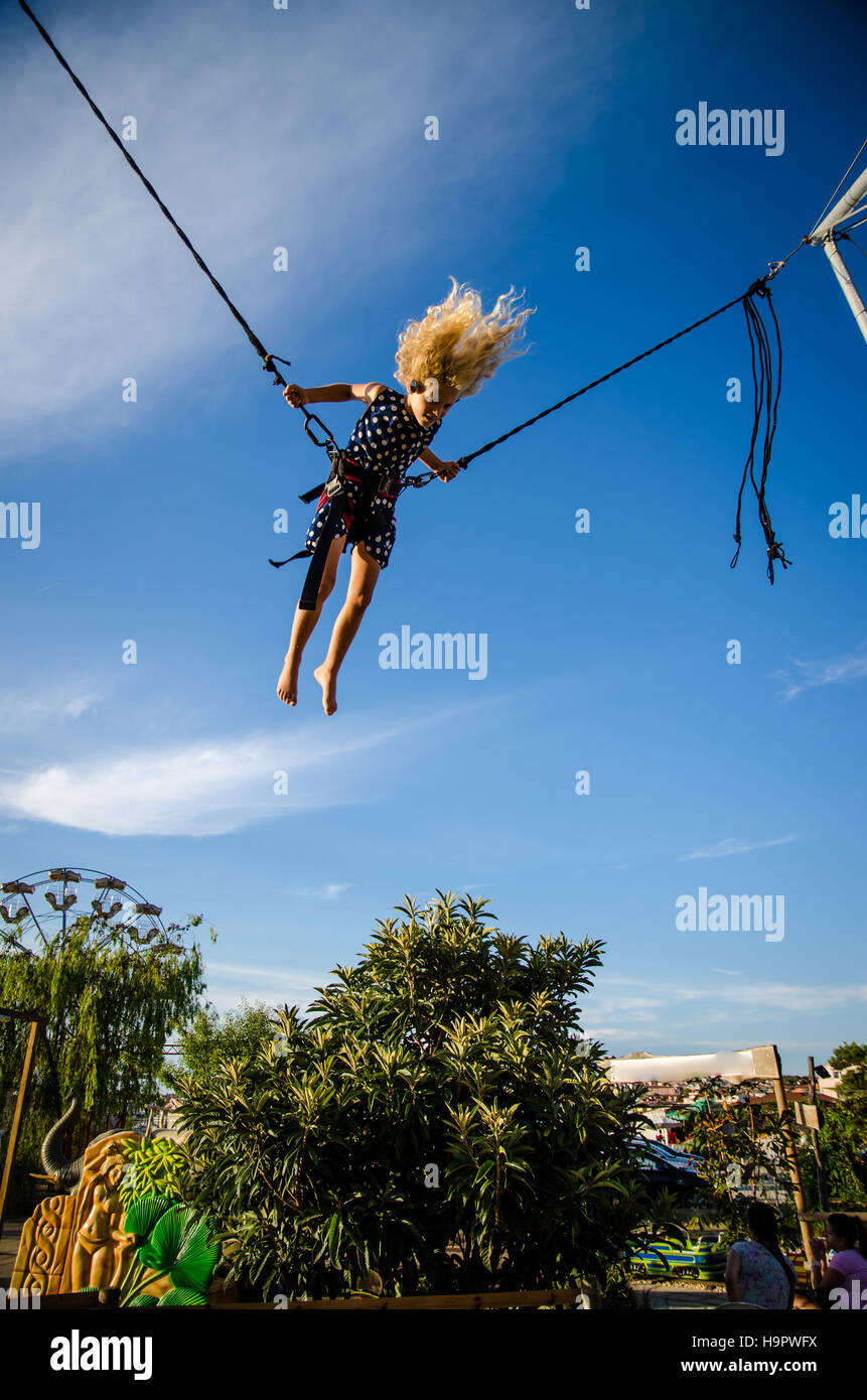 little girl with long blond hair spinning around in bungee attraction ...