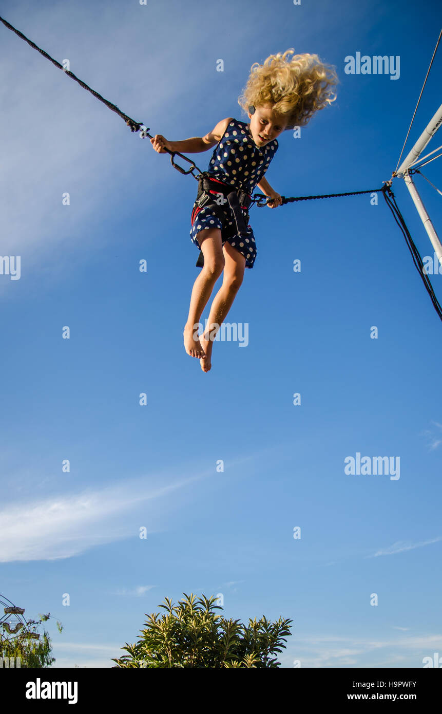 cute girl with long blond hair spinning around in bungee attraction ...