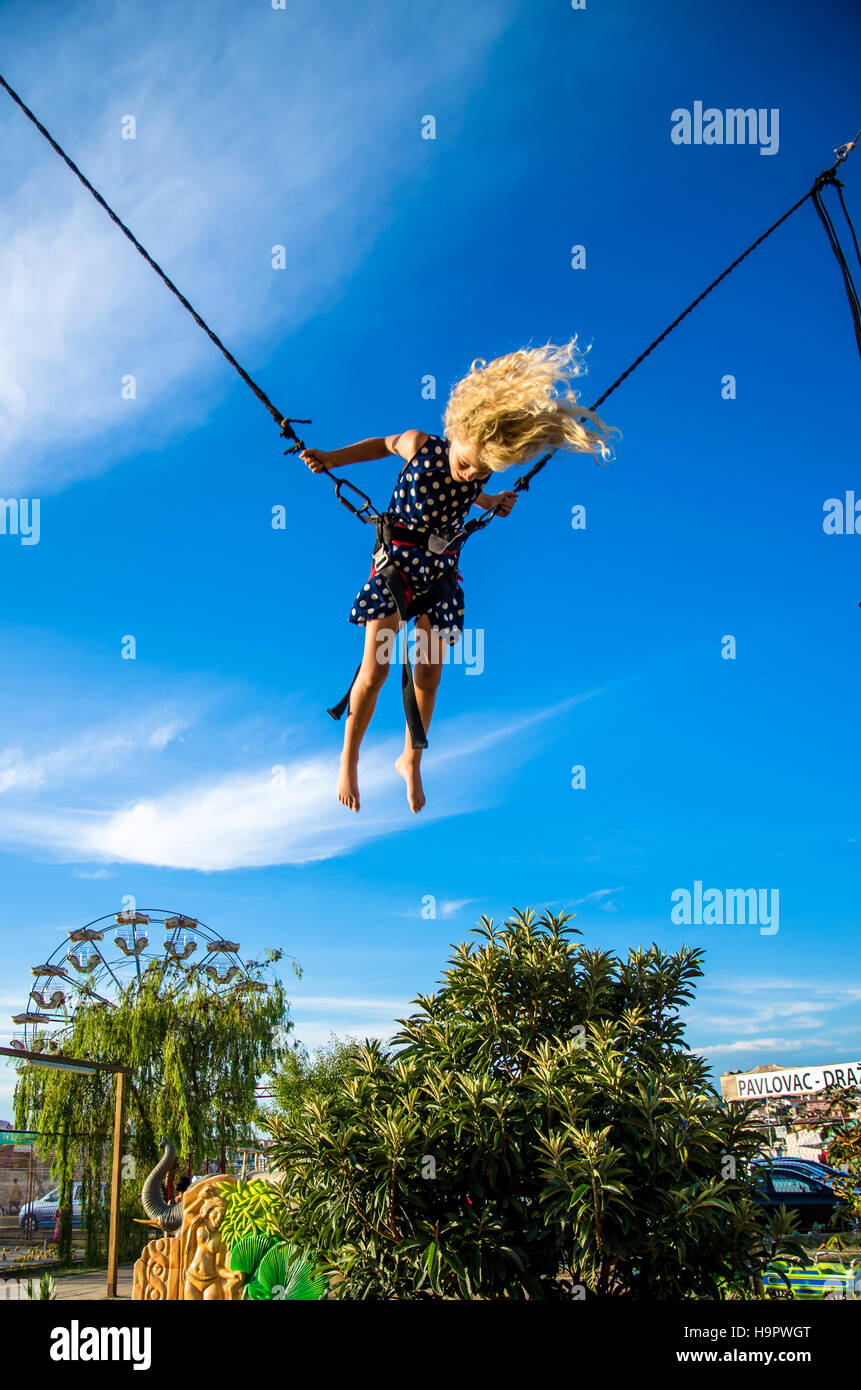 little child jumping in bungee attraction Stock Photo - Alamy