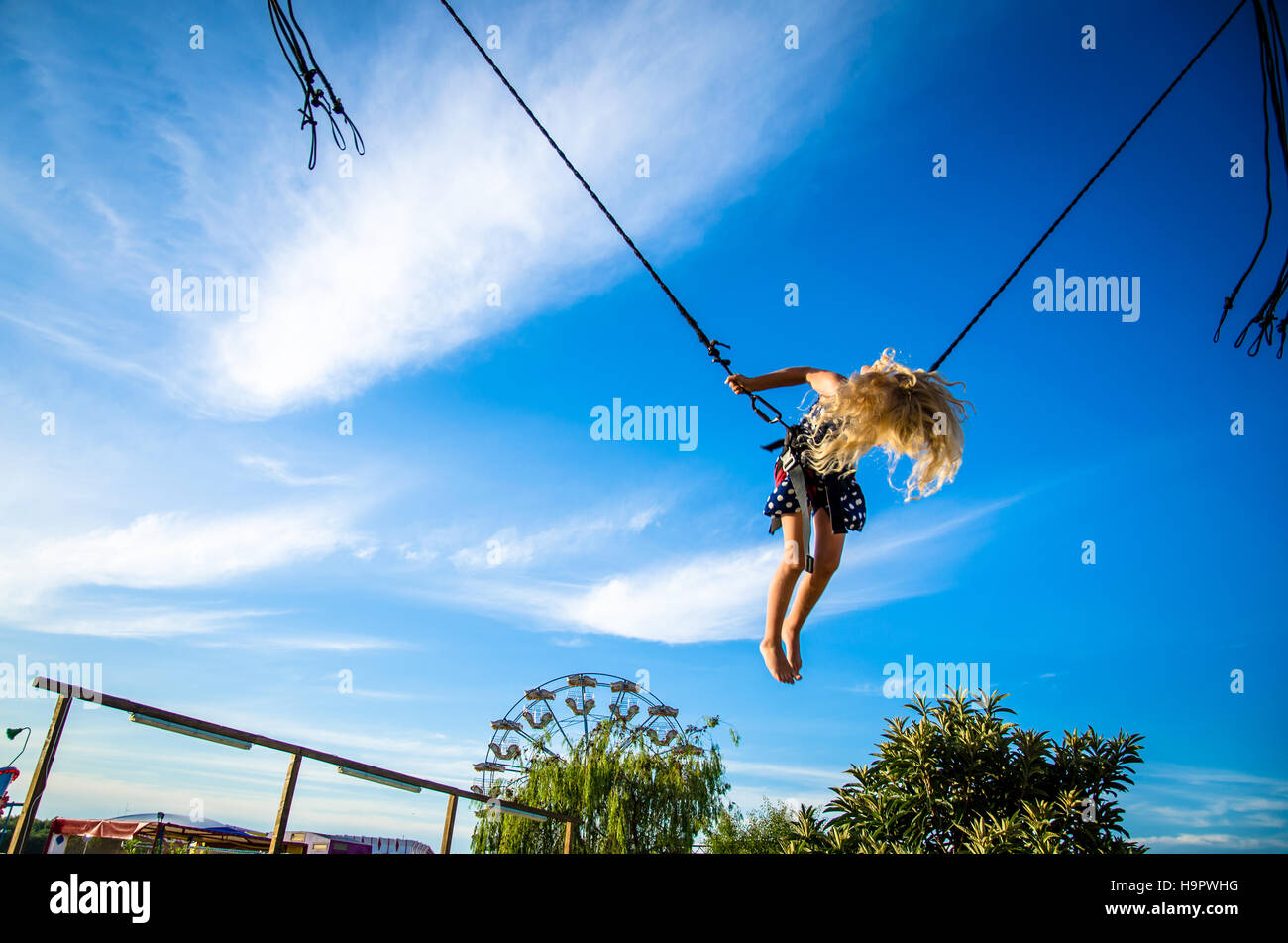 cute little girl with long blond hair blowing in the air jumping in ...