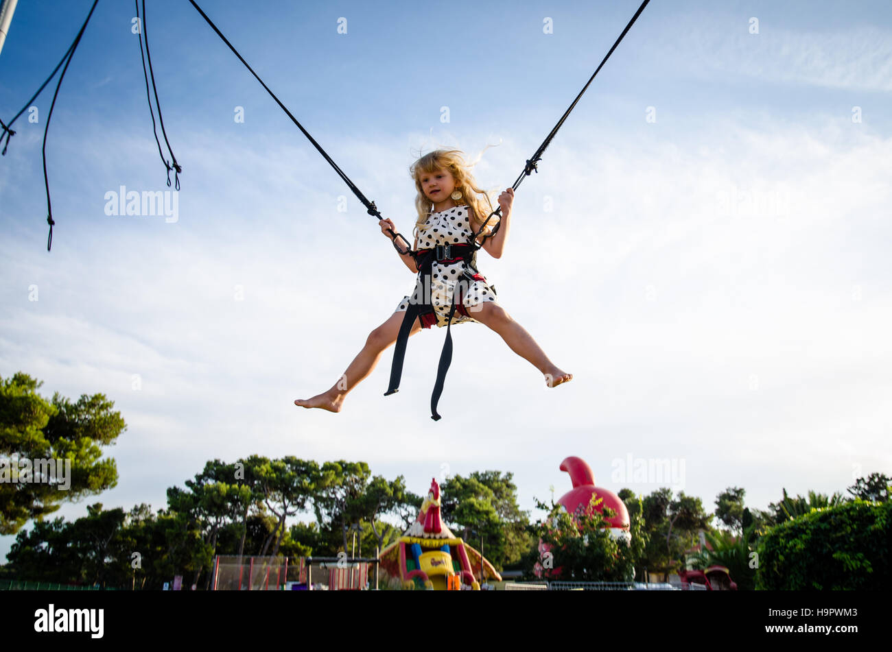 little cute girl jumping in bungee attraction Stock Photo - Alamy