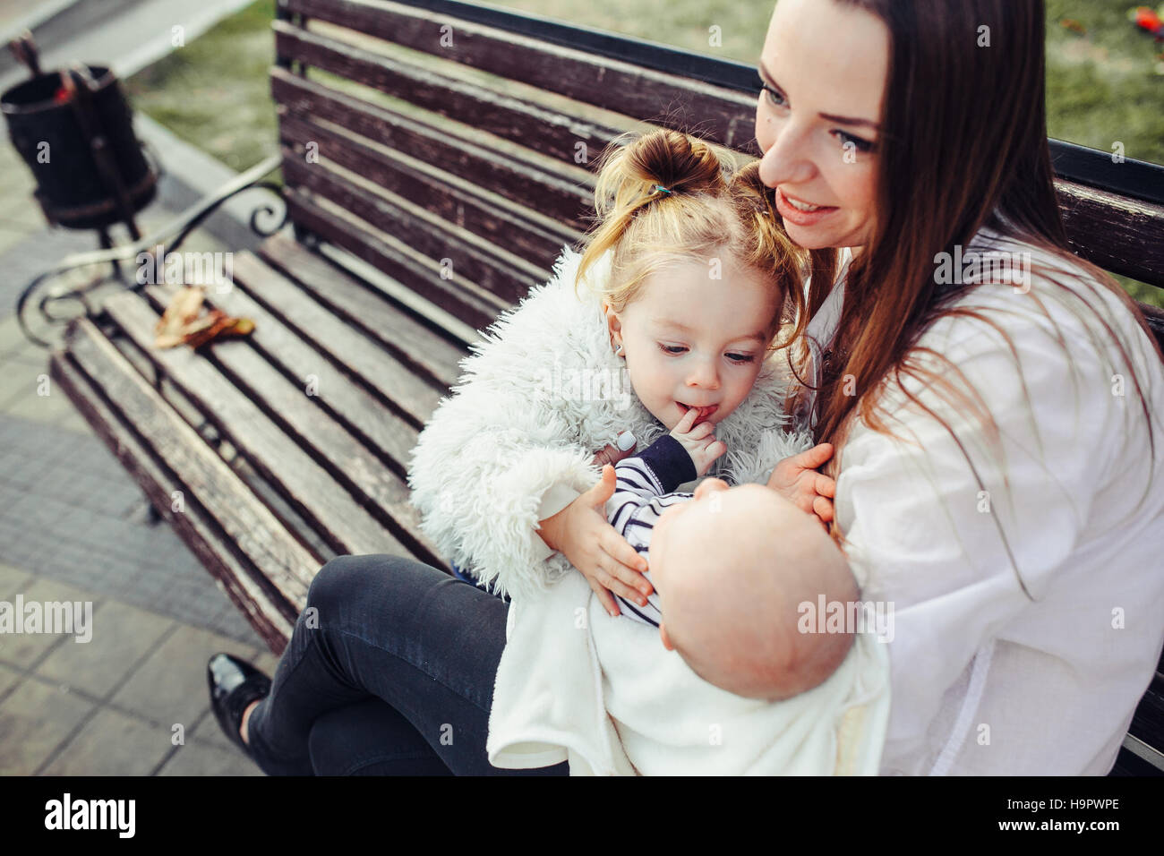 mother and two daughters rest on a bench Stock Photo - Alamy