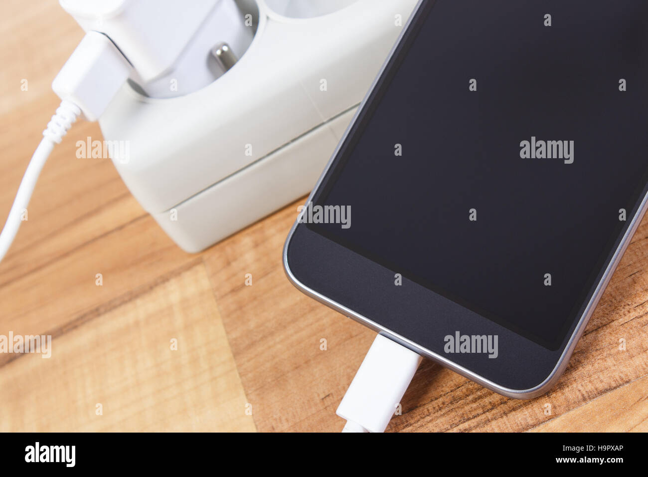 Mobile phone with connected plug of charger, smartphone charging on ...