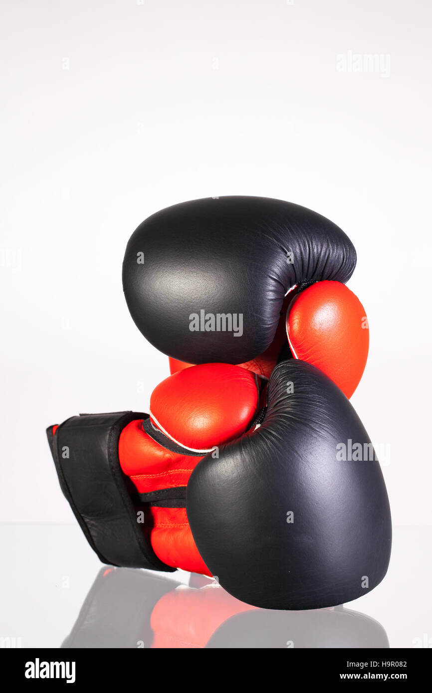 Red and black boxing gloves on a glass table isolated on white ...