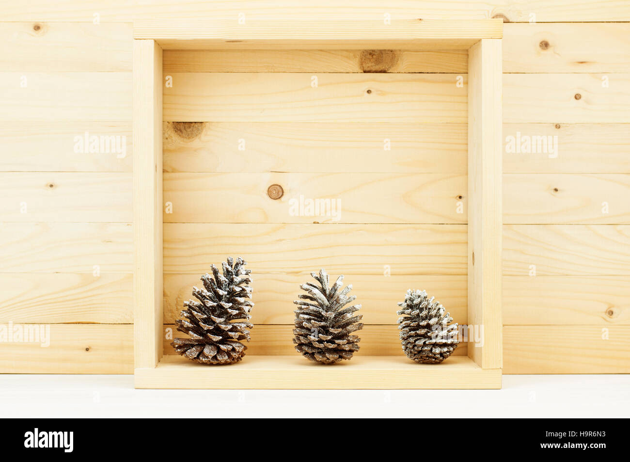 Still life of pine cones with snow in wooden square box. Christmas ...