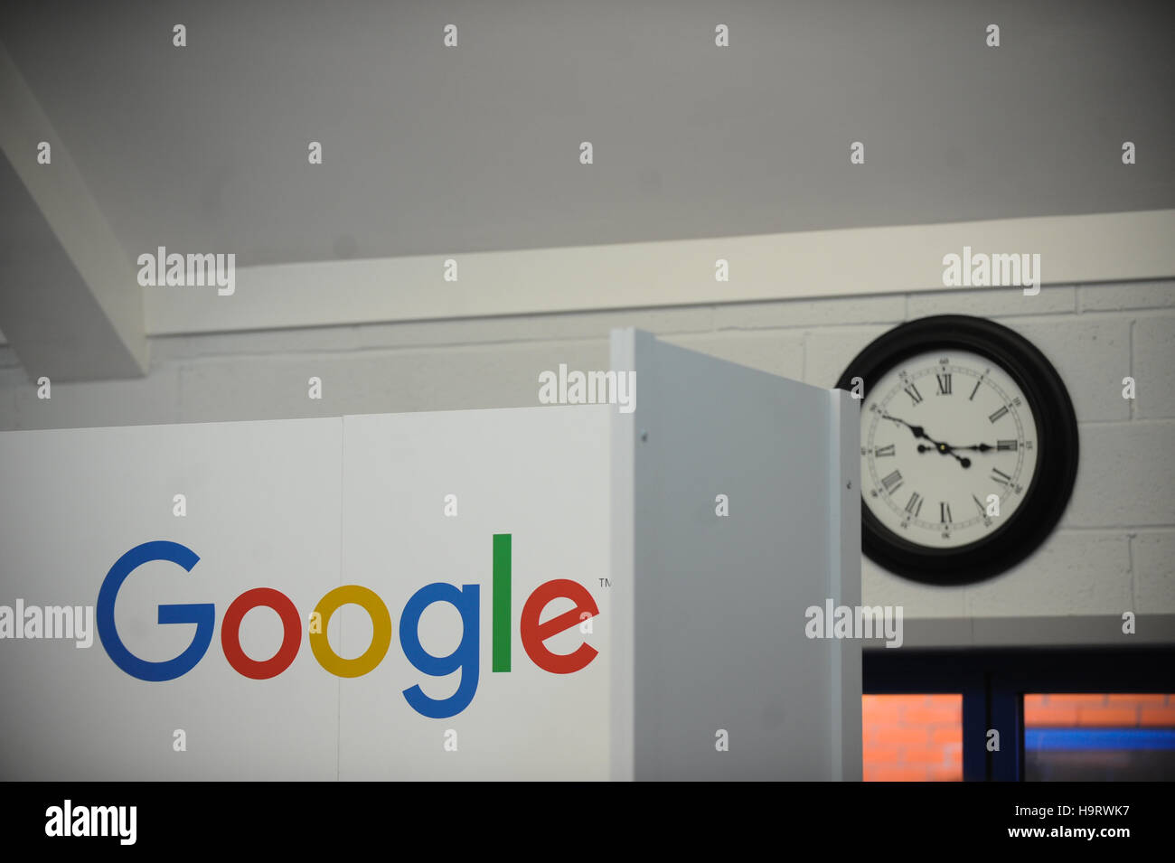 A Google logo on a wall with a clock behind it Stock Photo - Alamy