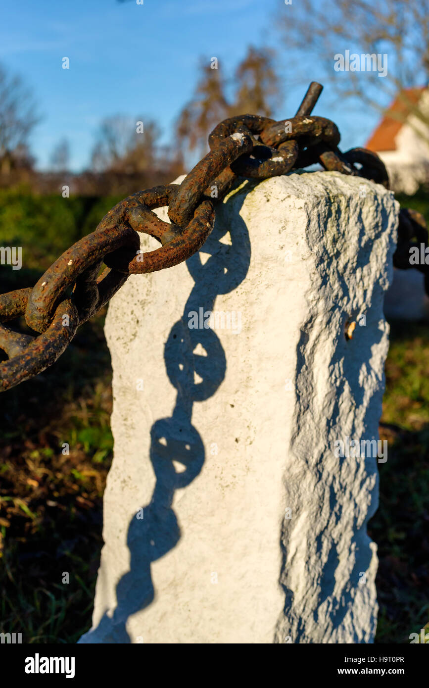 Rusty chain fence on white stone pillar Stock Photo - Alamy