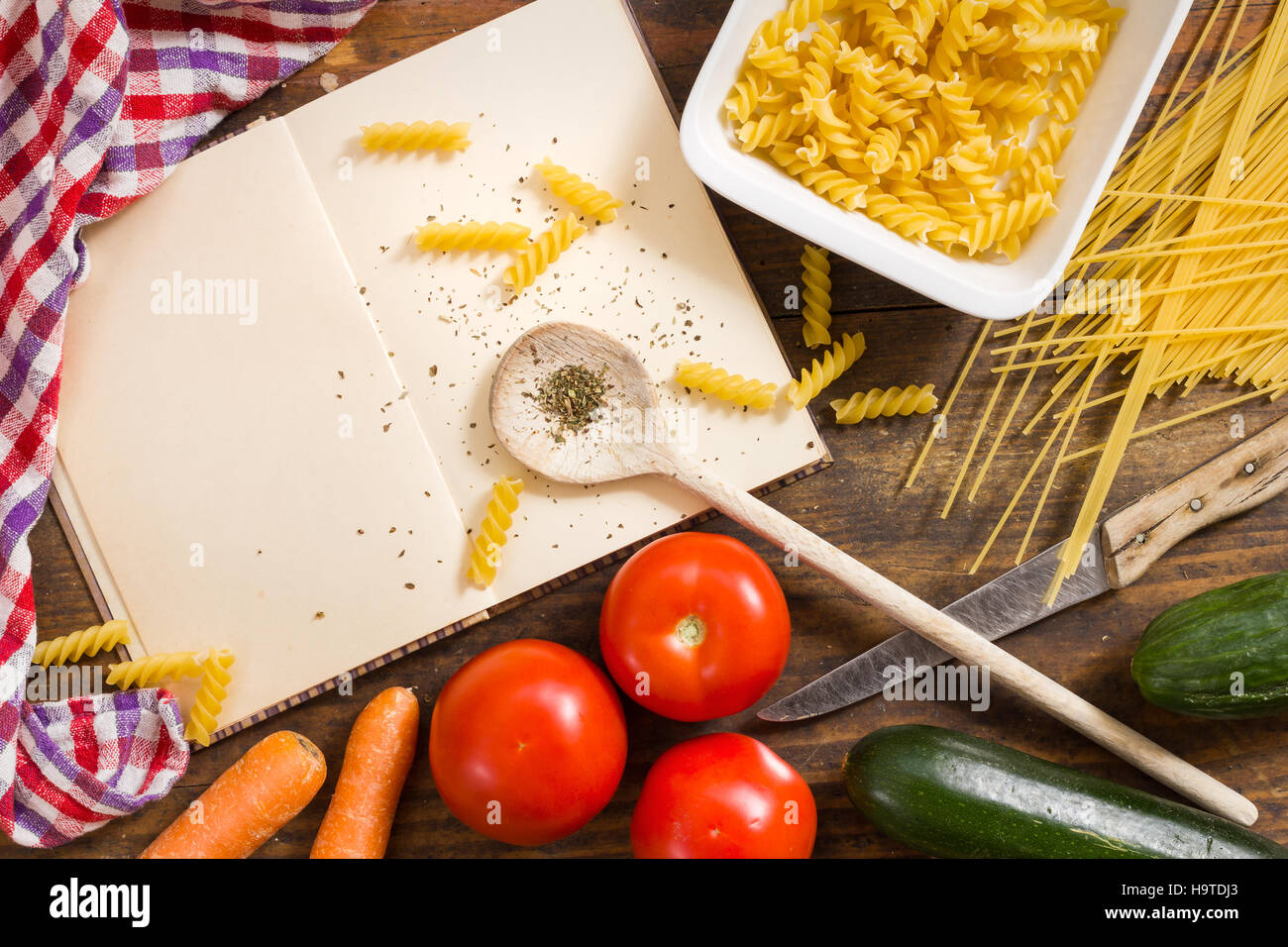 Opened cookbook with blank pages and noodles, cooking utensils ...
