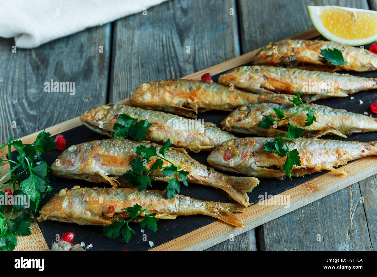 fried fish goatfish surmullet with lemon on board Stock Photo - Alamy