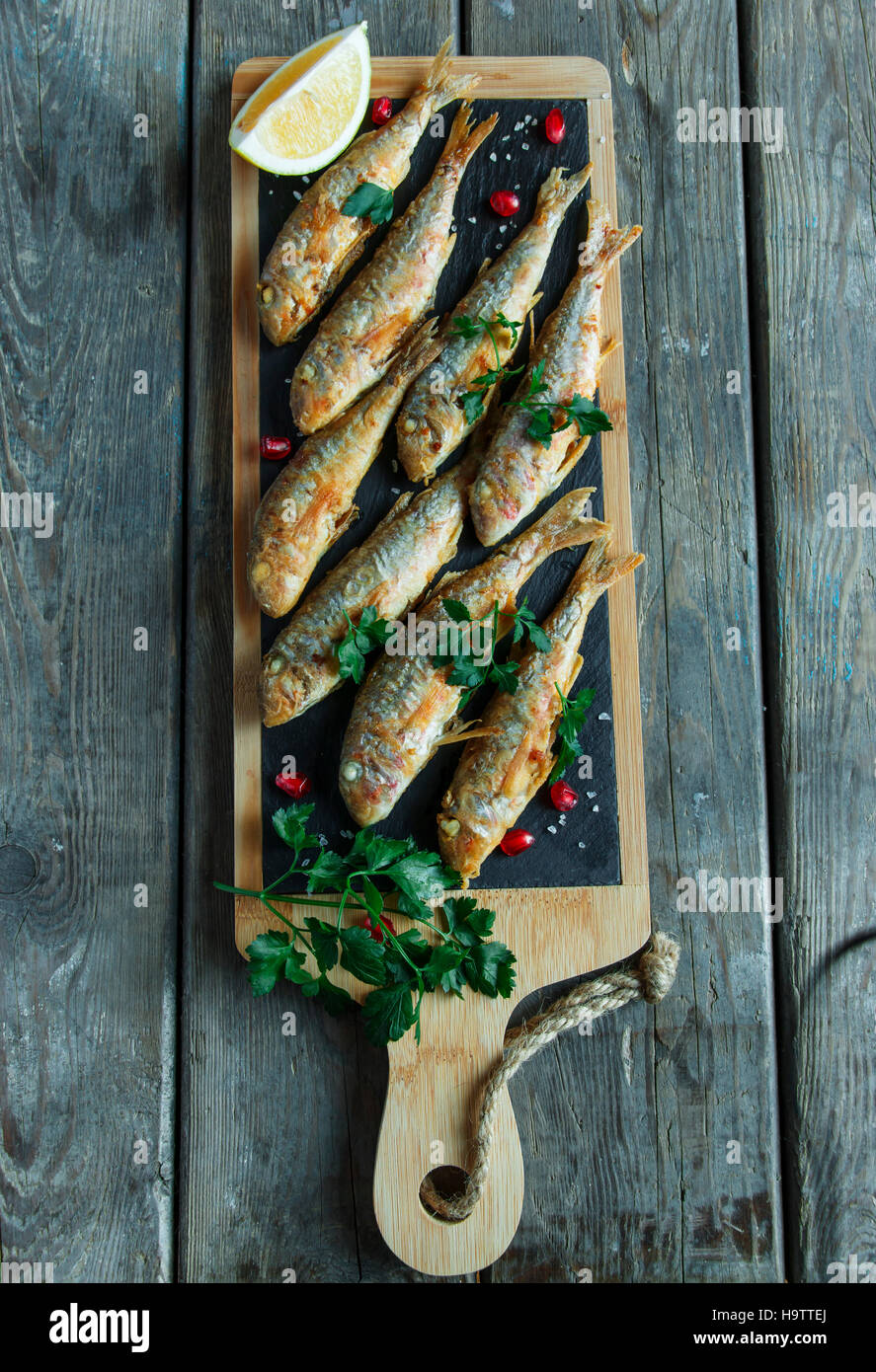 fried fish goatfish surmullet with lemon on board Stock Photo - Alamy
