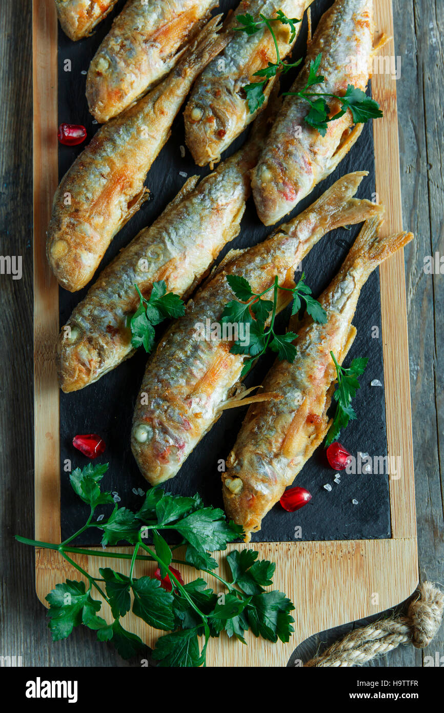 fried fish goatfish surmullet with lemon on board Stock Photo - Alamy