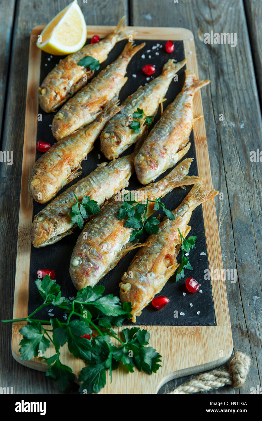 fried fish goatfish surmullet with lemon on board Stock Photo - Alamy