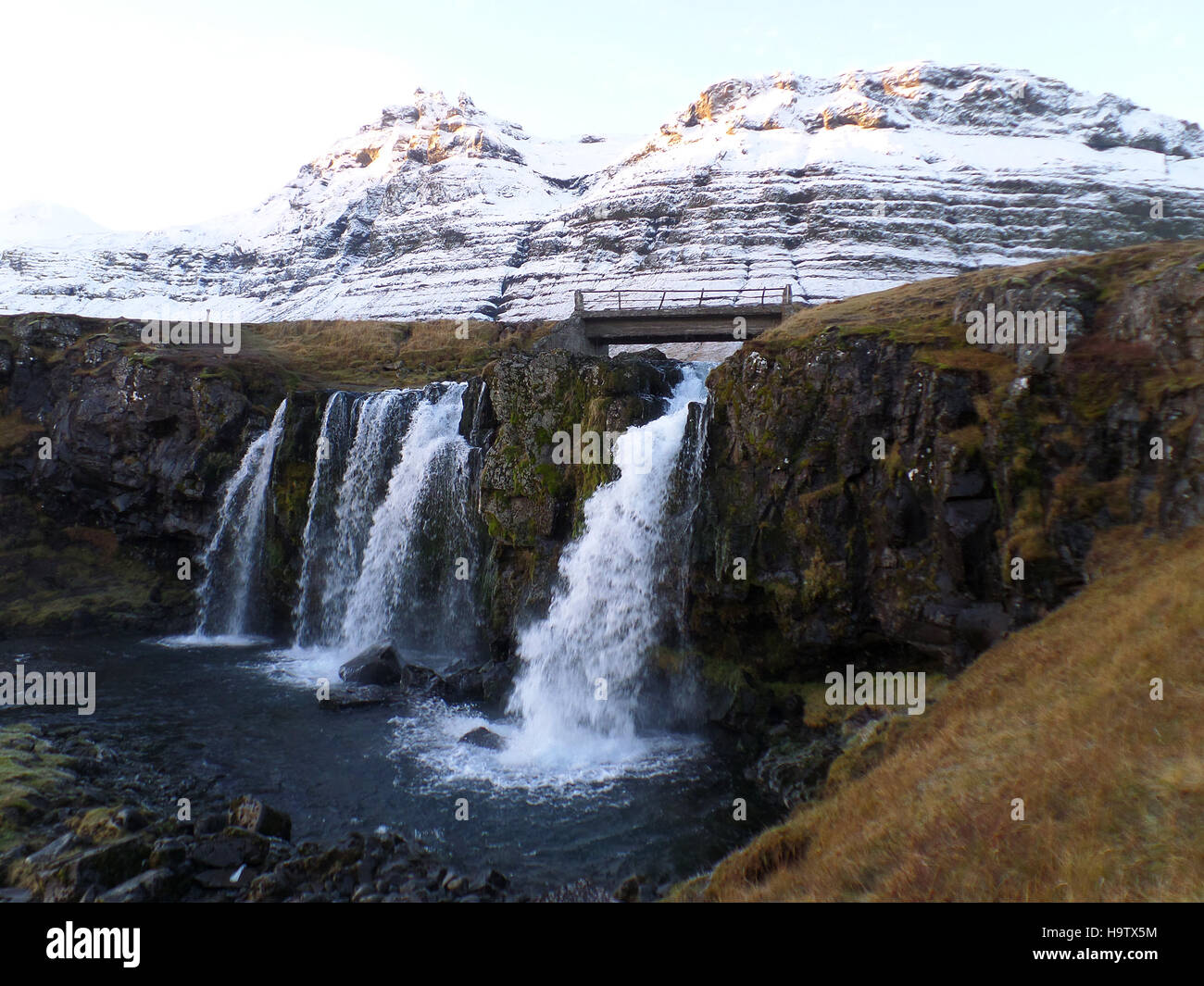 Scenic Kirkjufellsfoss waterfall with snow capped mountain in the ...