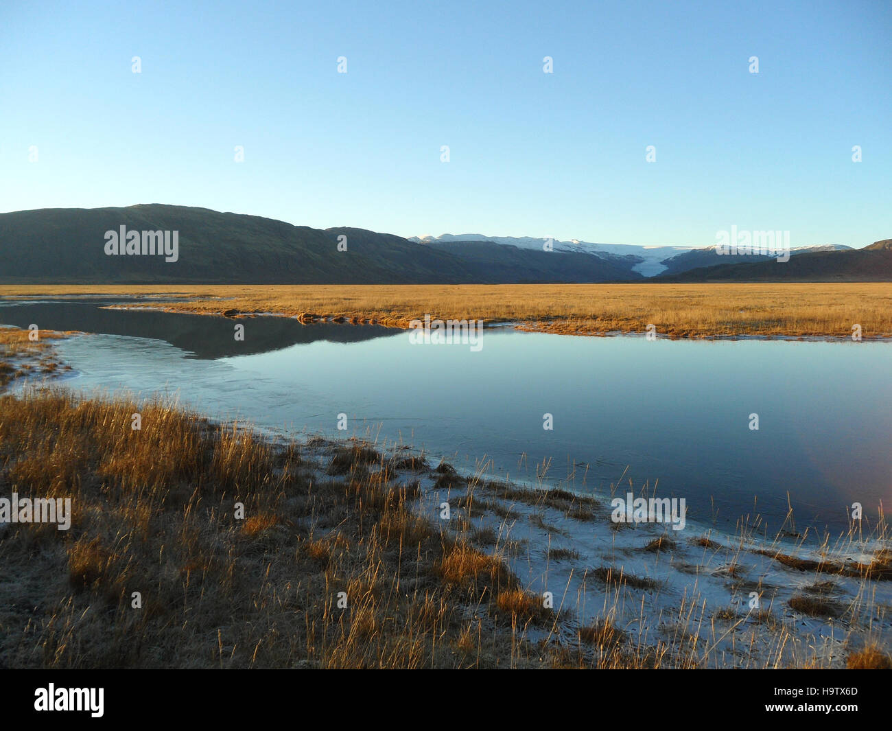 Reflection of mountain range and blue sky on a freezing lake, the ...