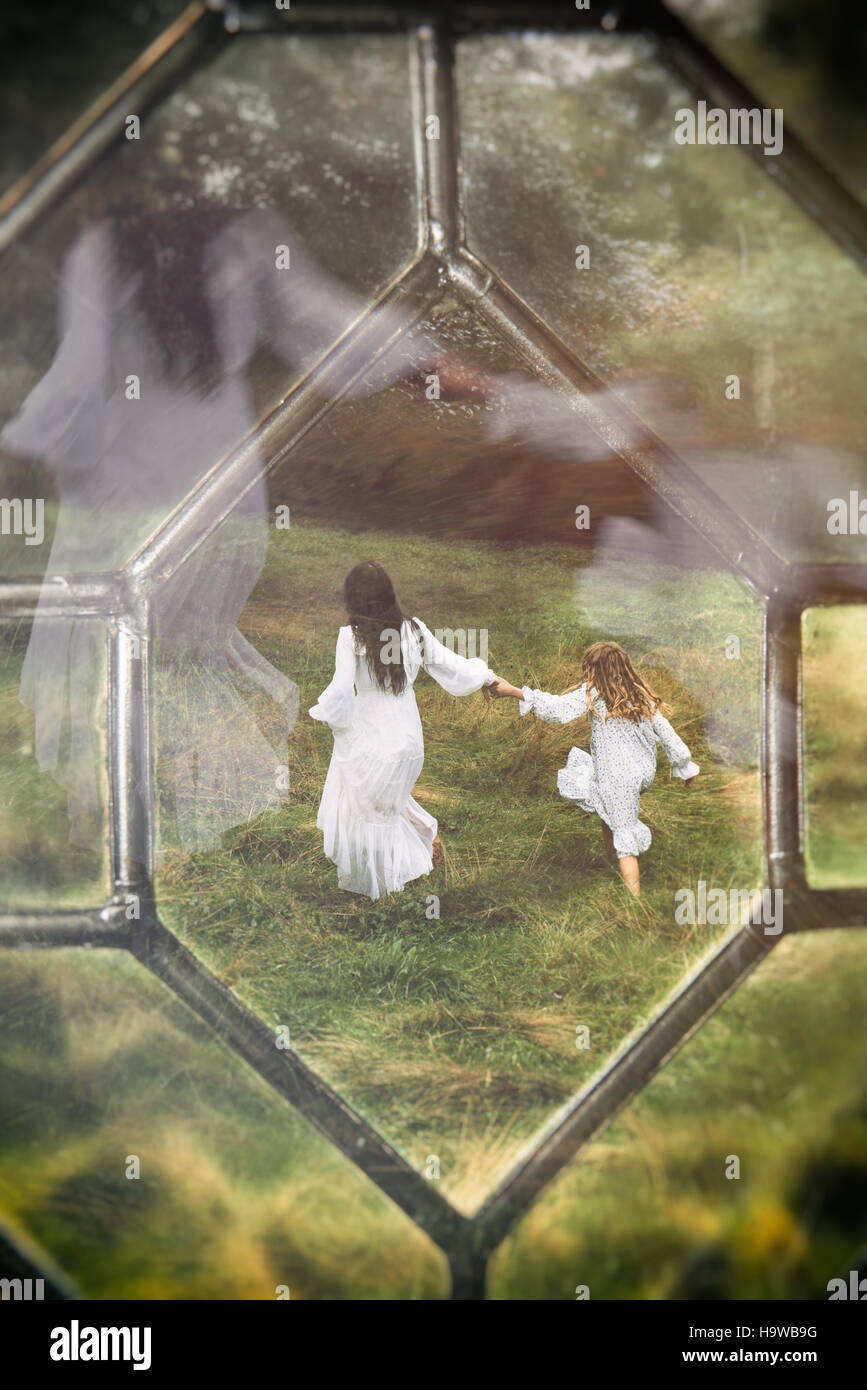 Woman and girl running through long grass as seen through an old leaded ...