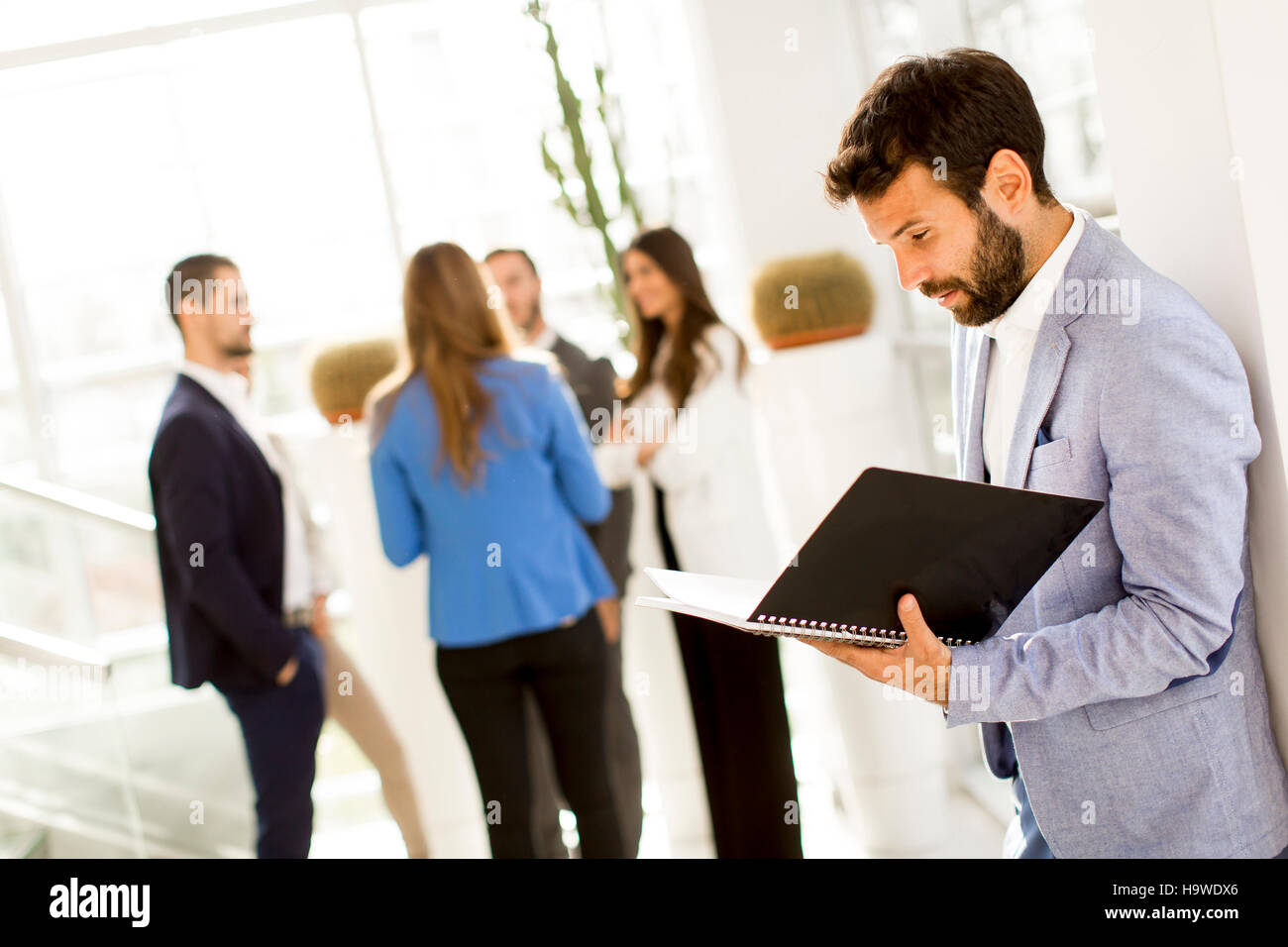 Young businessman looking at documents while other young business ...