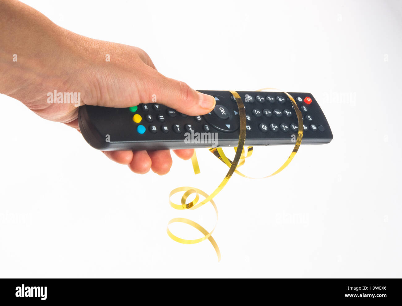 hand holding a remote control in a festive gold ribbon on white ...
