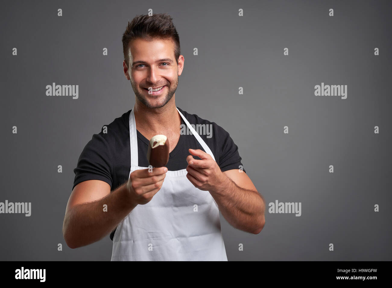 A handsome young barista man smiling and offering an ice-cream Stock ...