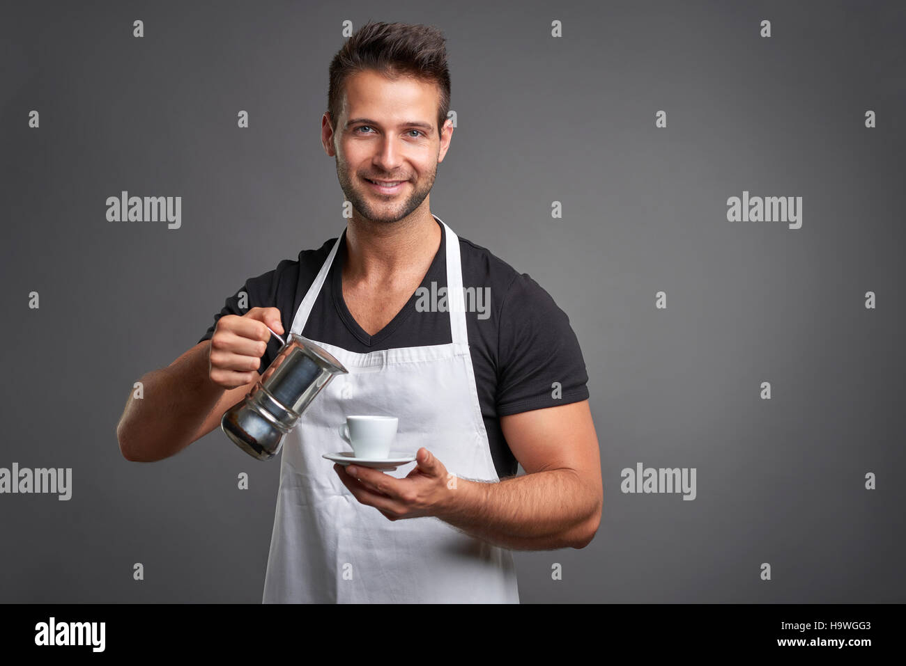 A young barista man smiling and pouring coffee from a percolator to a ...