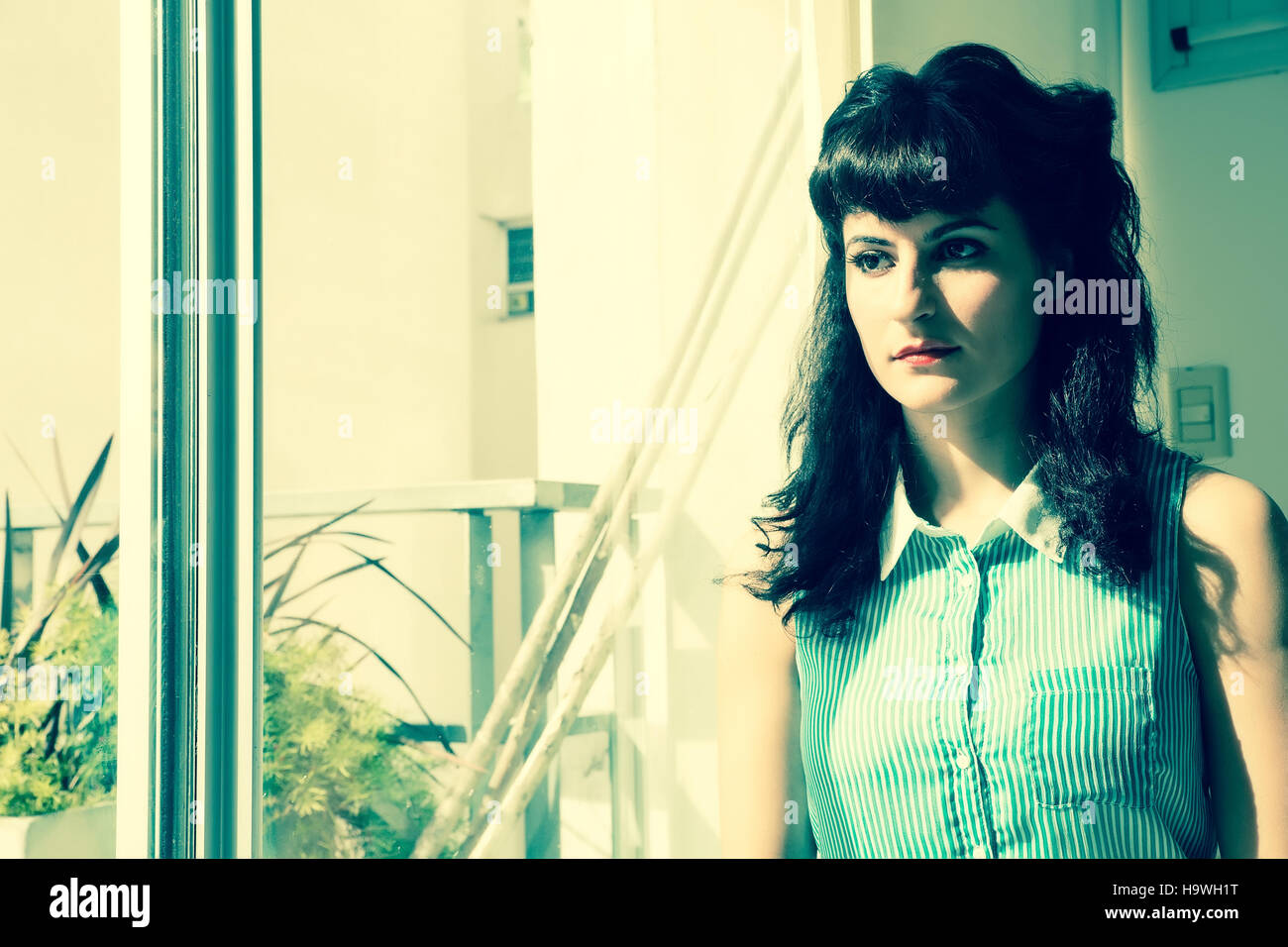 A vintage styled woman sitting beside the window Stock Photo - Alamy