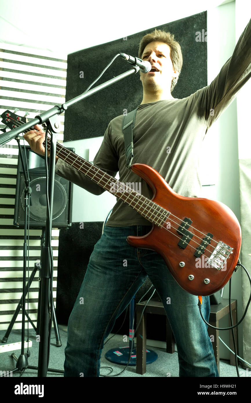 A Rock musician playing passionately bass in the rehearsal Studio Stock ...