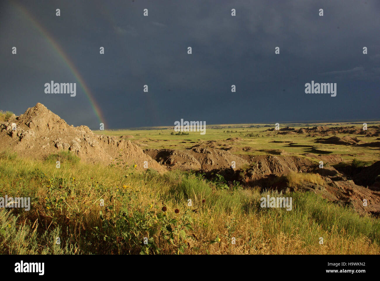 A vibrant rainbow arches over the rolling prairies of Badlands National ...
